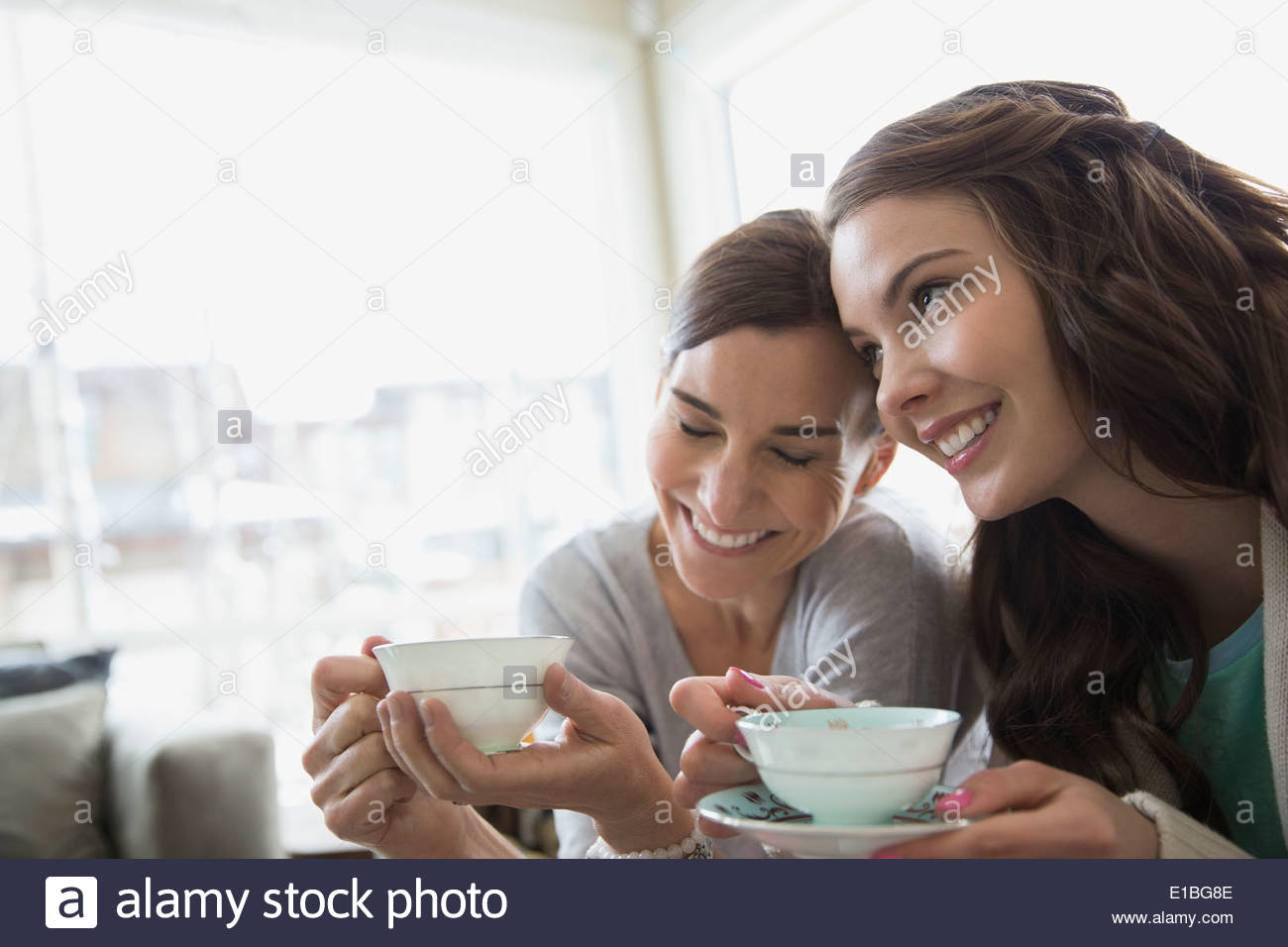 Mother and daughter drinking tea in living room Stock Photo - Alamy