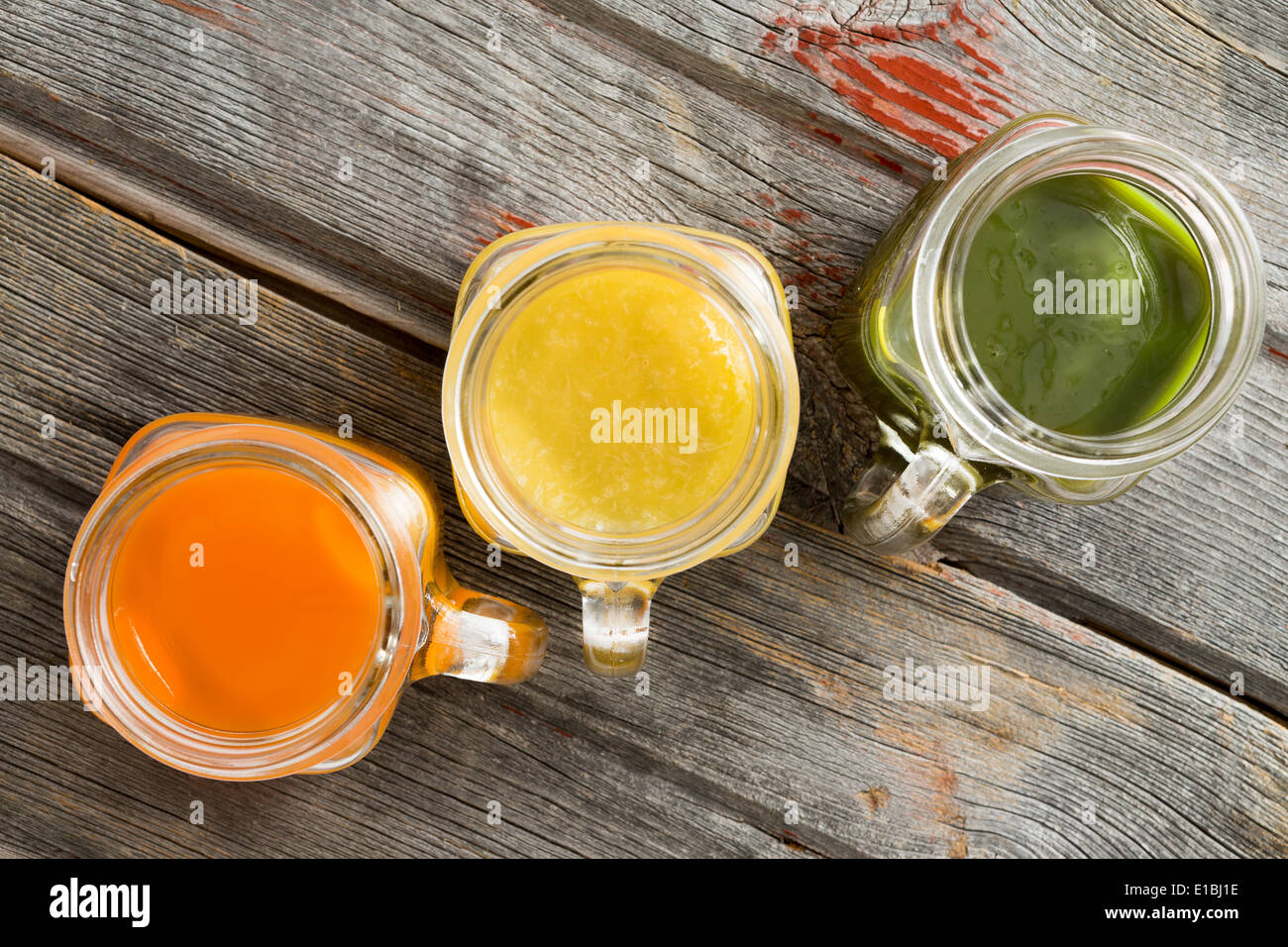 View from above of a colorful trio of fresh fruit juice in glass jugs ...