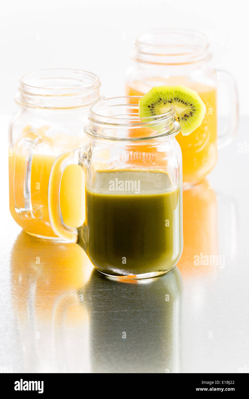Glass jars of fresh tropical fruit juice on a metal surface with ...