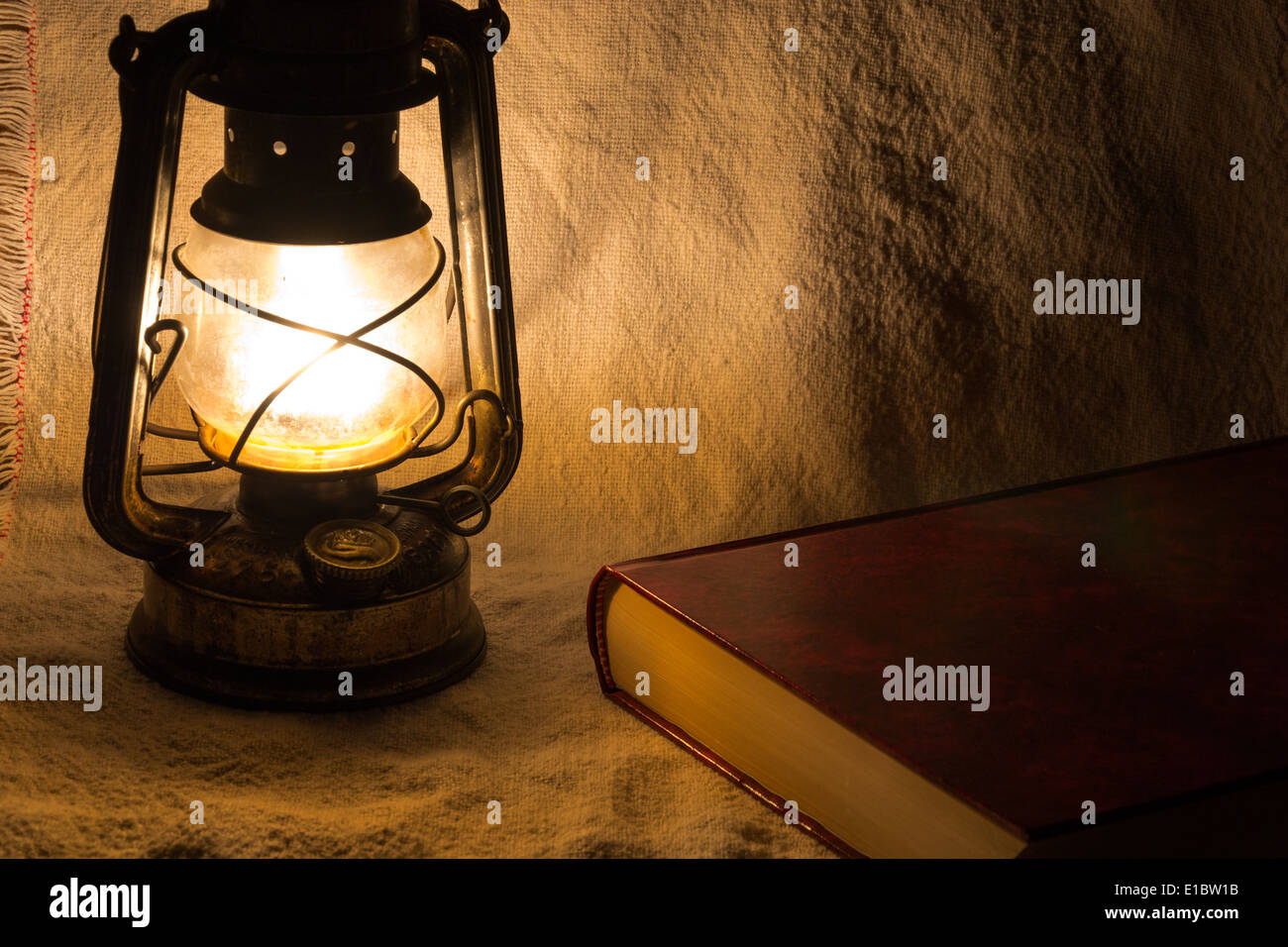 Set with an old rusty lantern and a book Stock Photo - Alamy