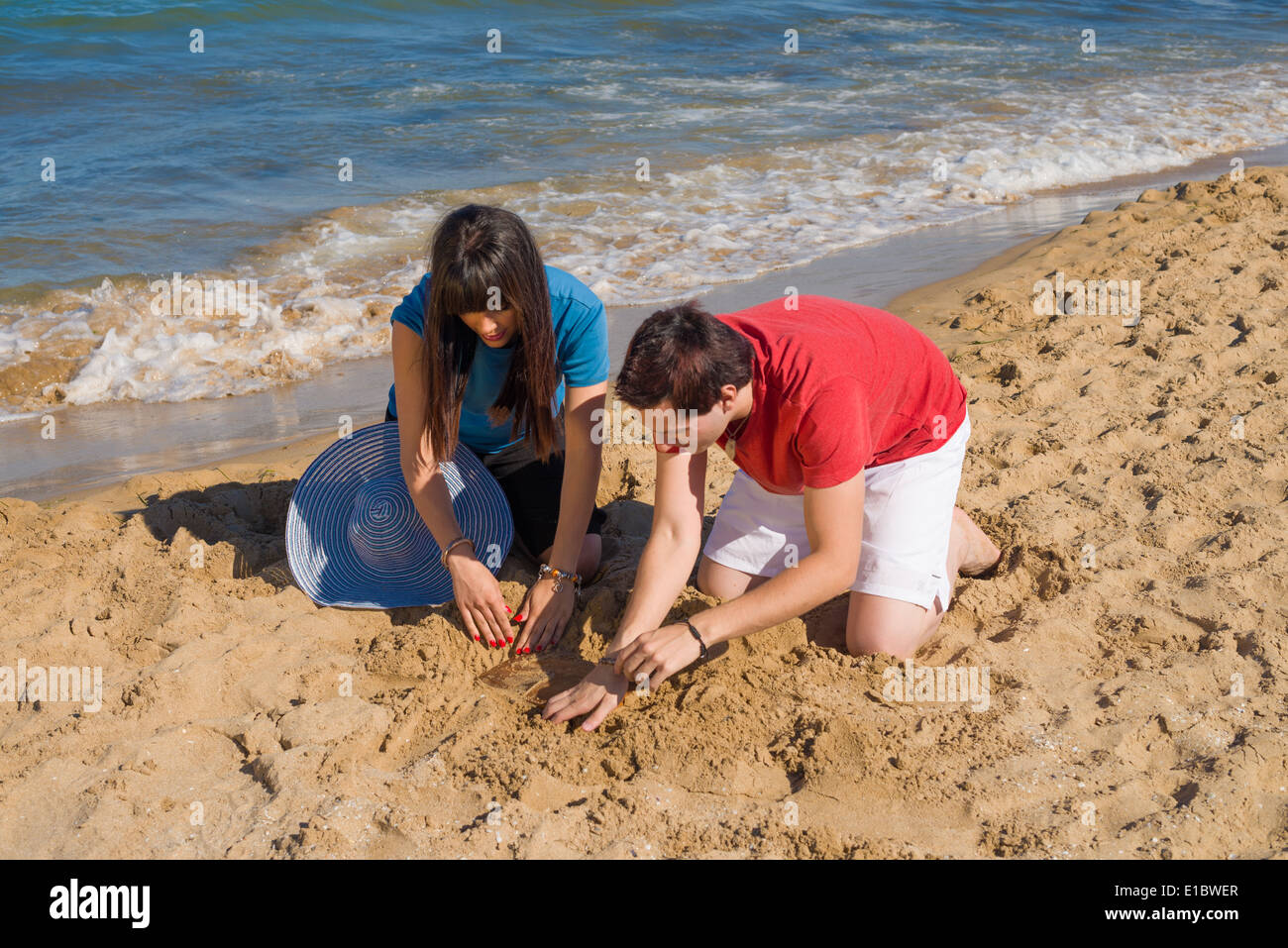 Couple digging on beach sand to find a treasure Stock Photo - Alamy