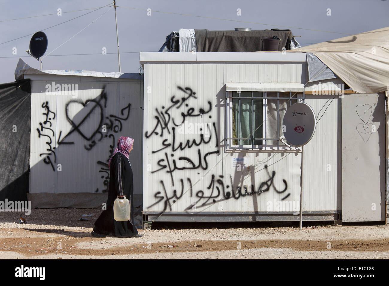 Al Mafraq, JORDAN. 31st Jan, 2014. A woman carries water past a Caravan ...