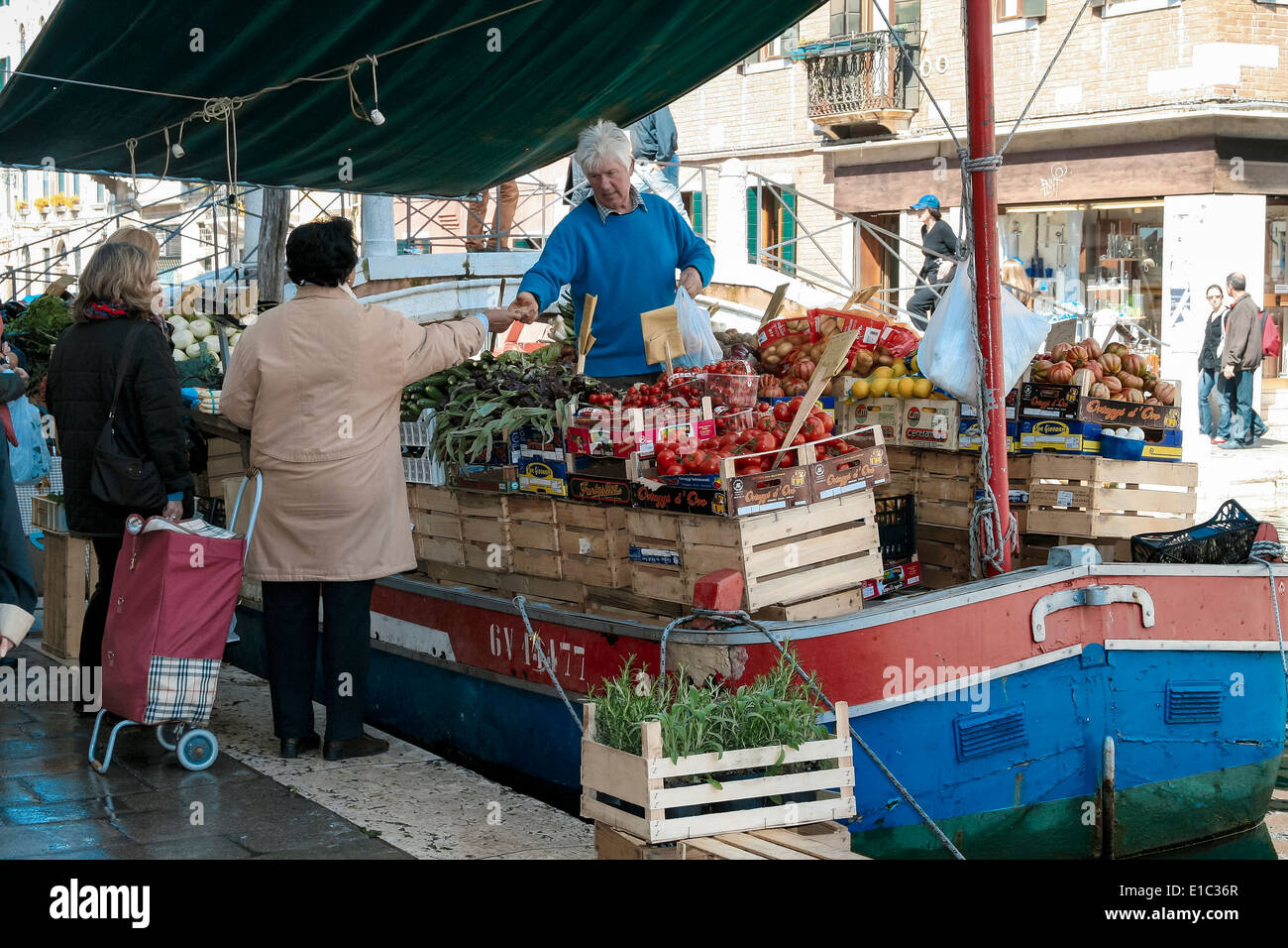 Fruit and vegetable seller selling produce to customers from canal boat ...