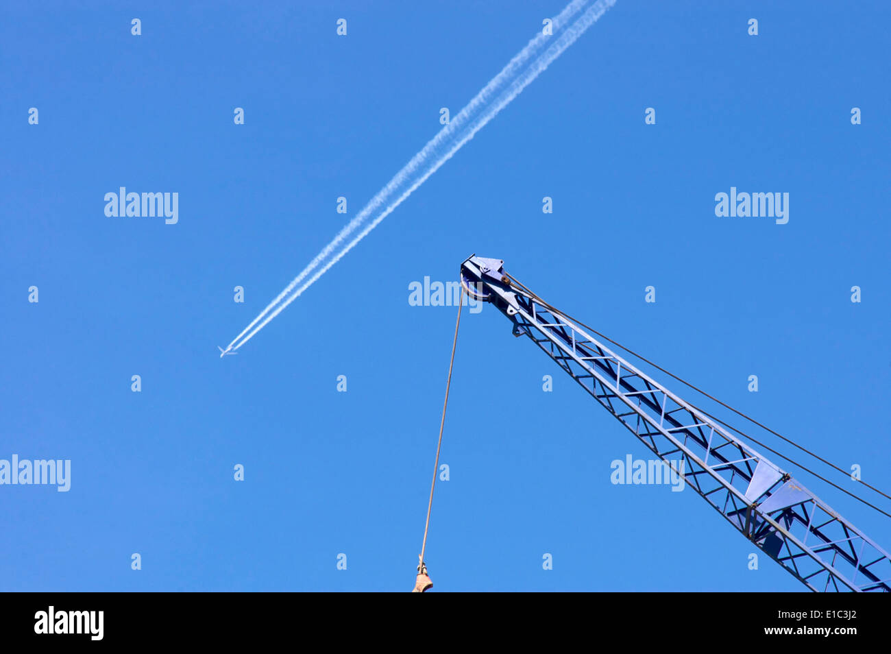 Crane and high flying jet plane in blue sky Stock Photo - Alamy