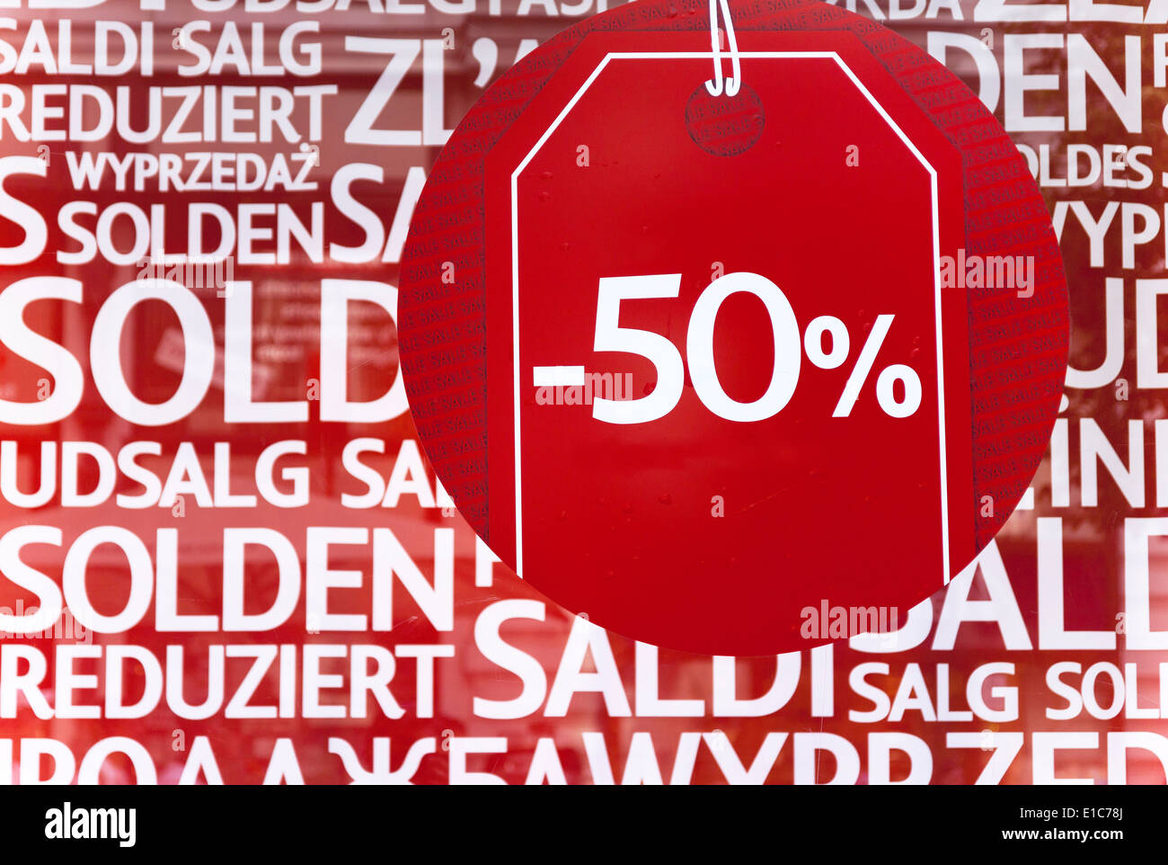 Shop window display with text Sale in different languages on red poster ...