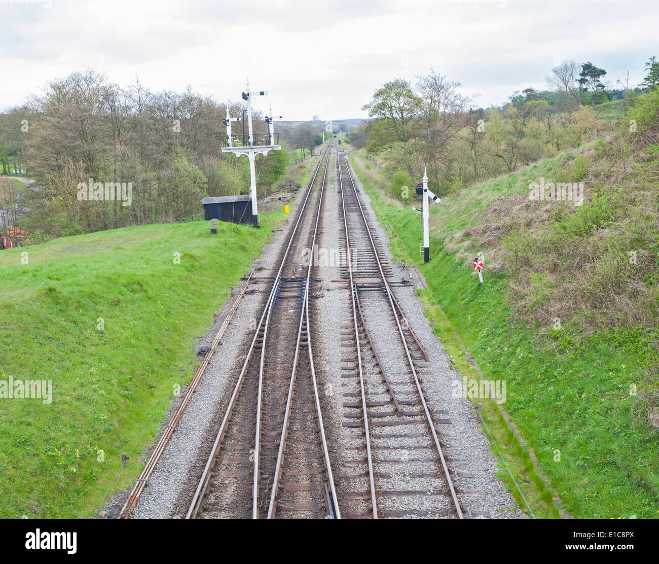 View down railway track in english rural countryside with overcast sky ...