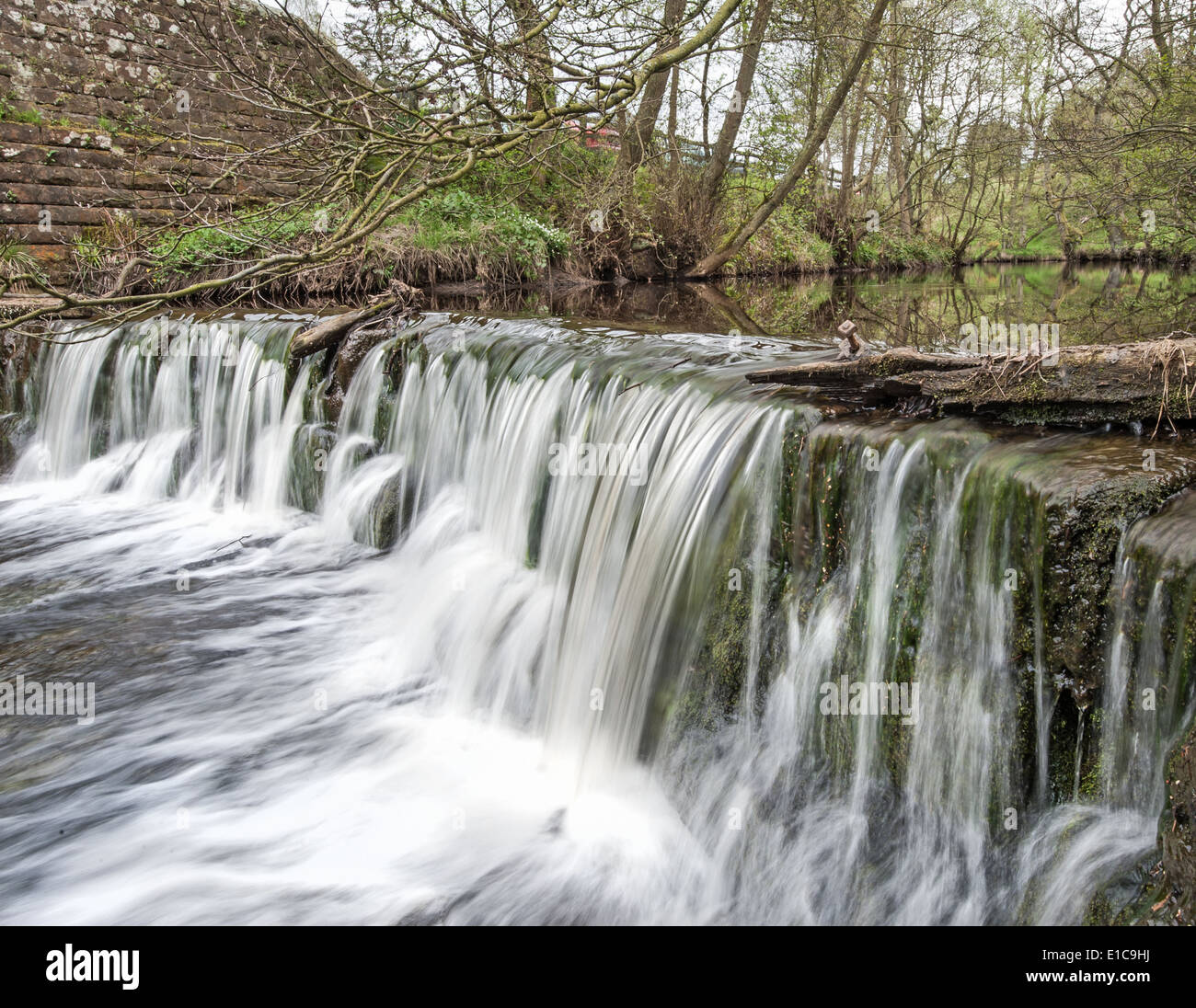 Water from a small river flowing with blurred motion over little ...
