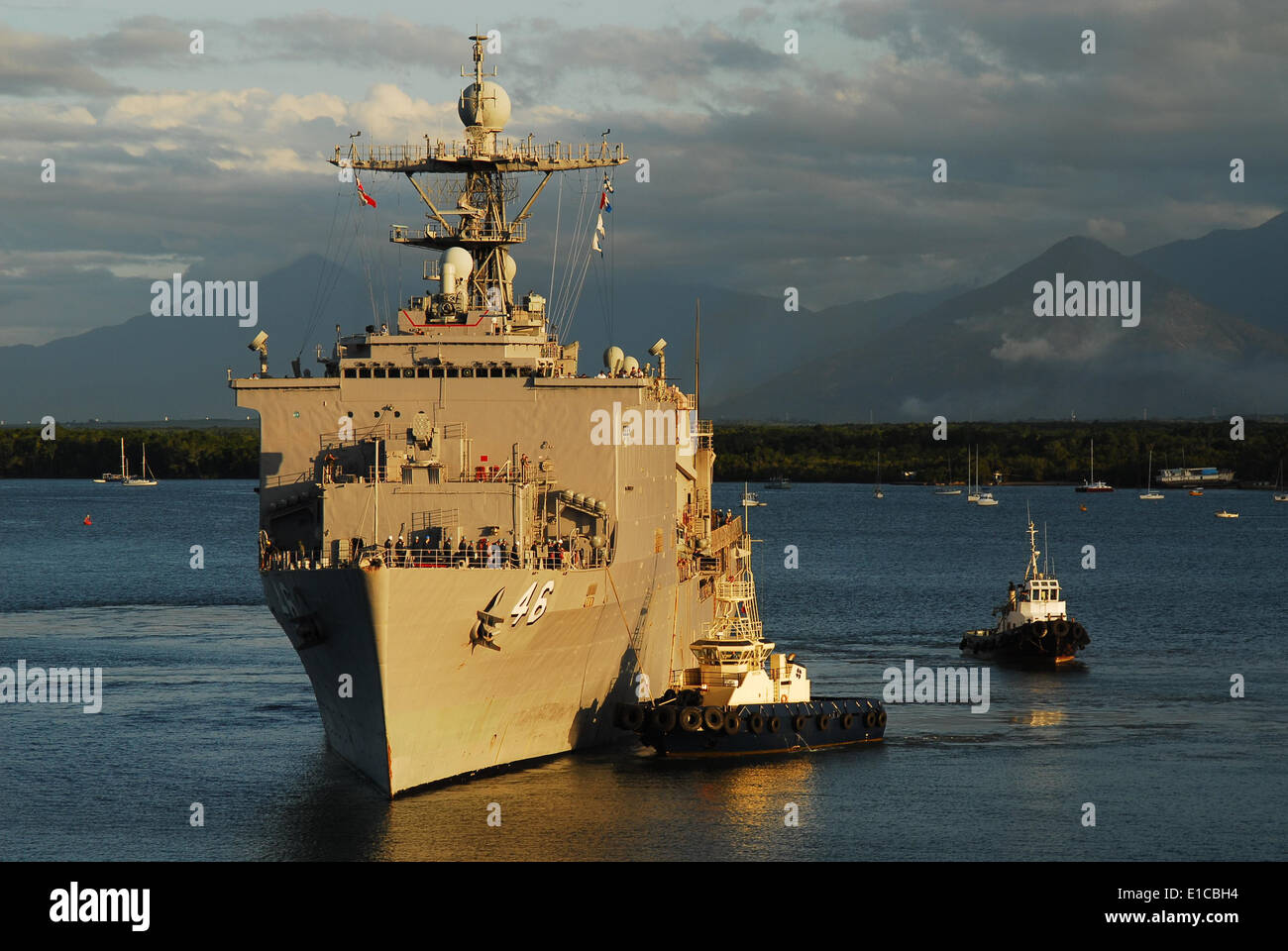 A small boat helps the dock landing ship USS Tortuga (LSD 46) navigate ...