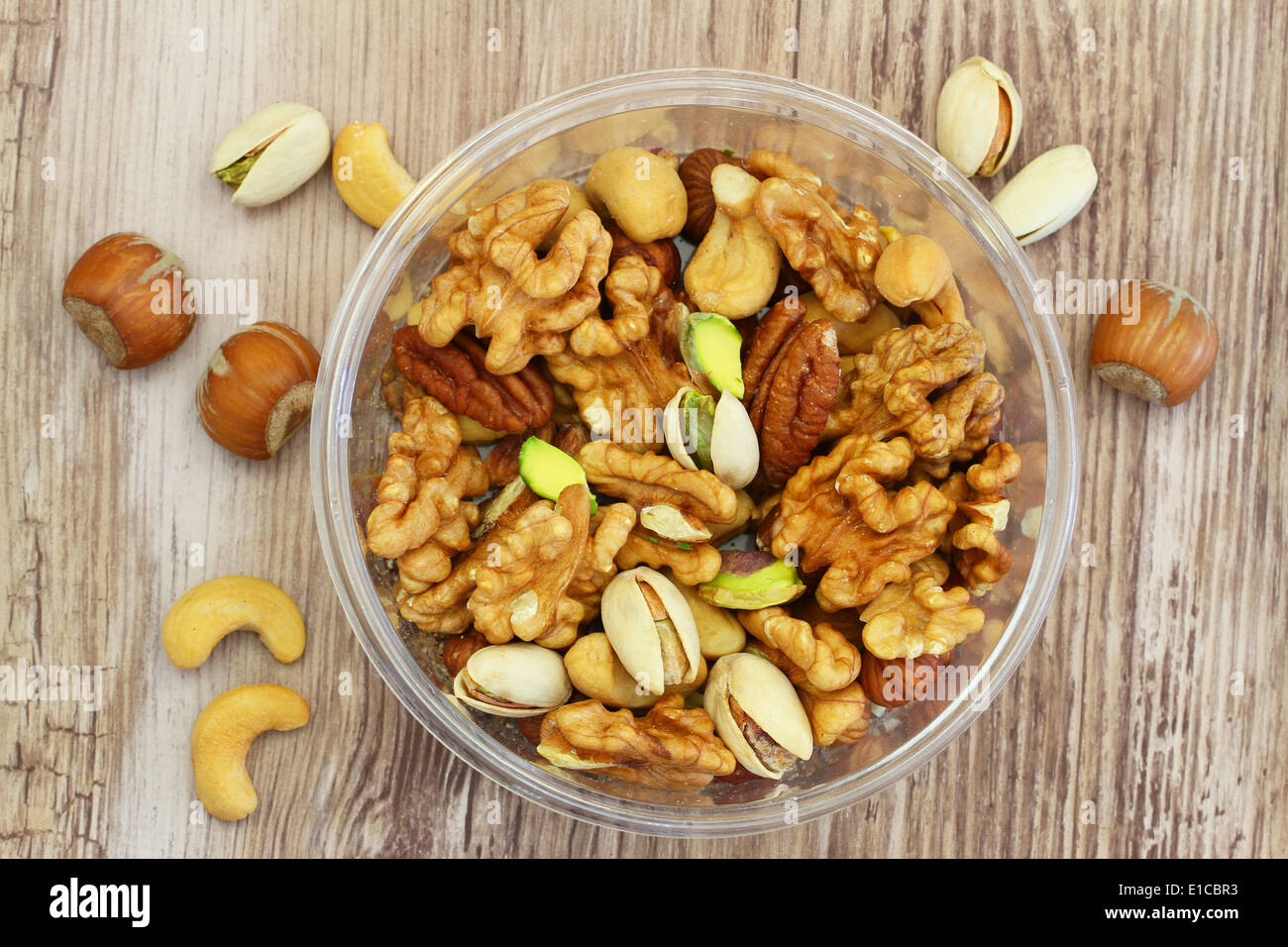 Selection of mixed nuts in plastic box on wooden surface Stock Photo ...