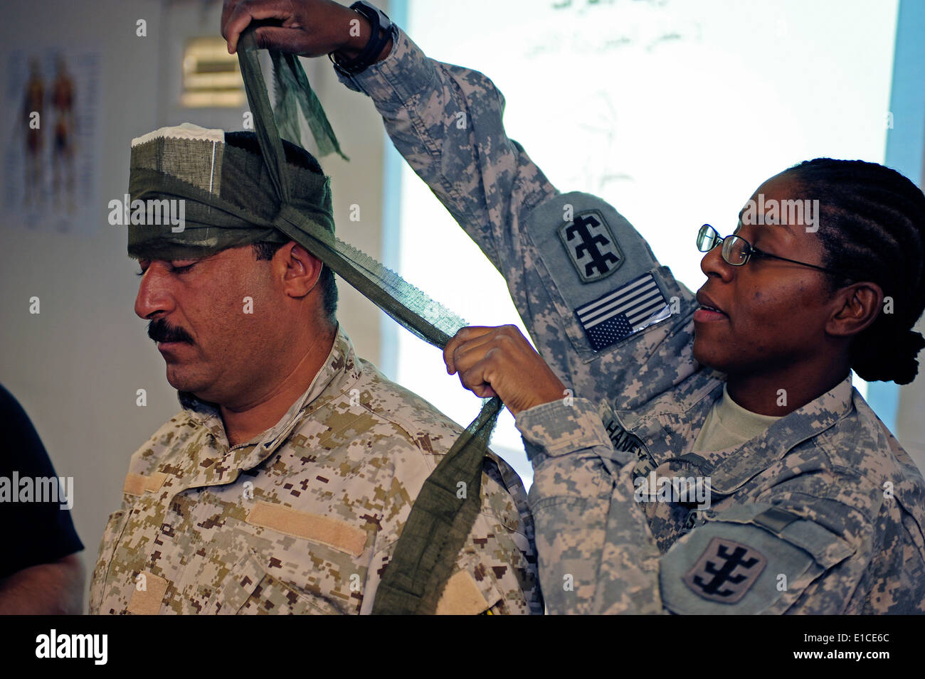 U.S. Army Spc. Lisa Haney demonstrates to Iraqi soldiers how to dress a ...