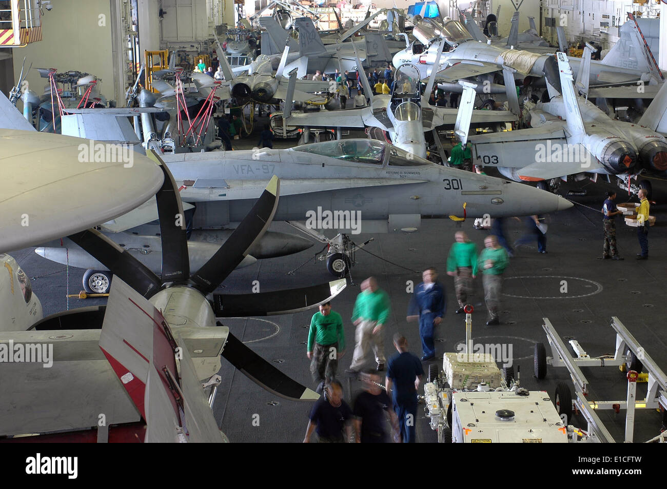 U.S. Sailors move through the hangar bay aboard aircraft carrier USS ...
