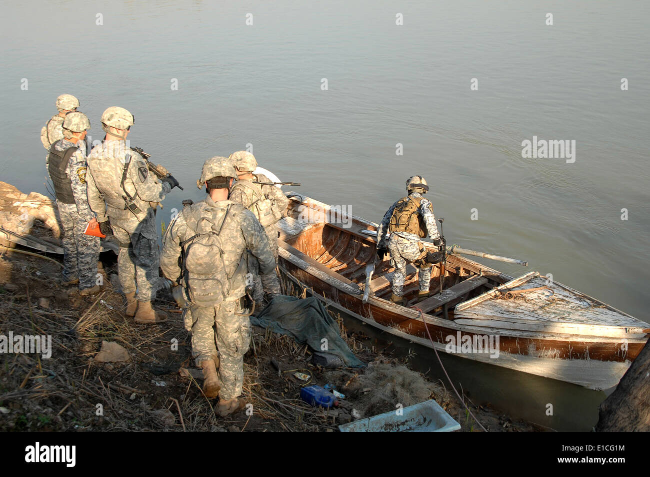U.S. and Iraqi soldiers search a boat for improvised explosive devices ...