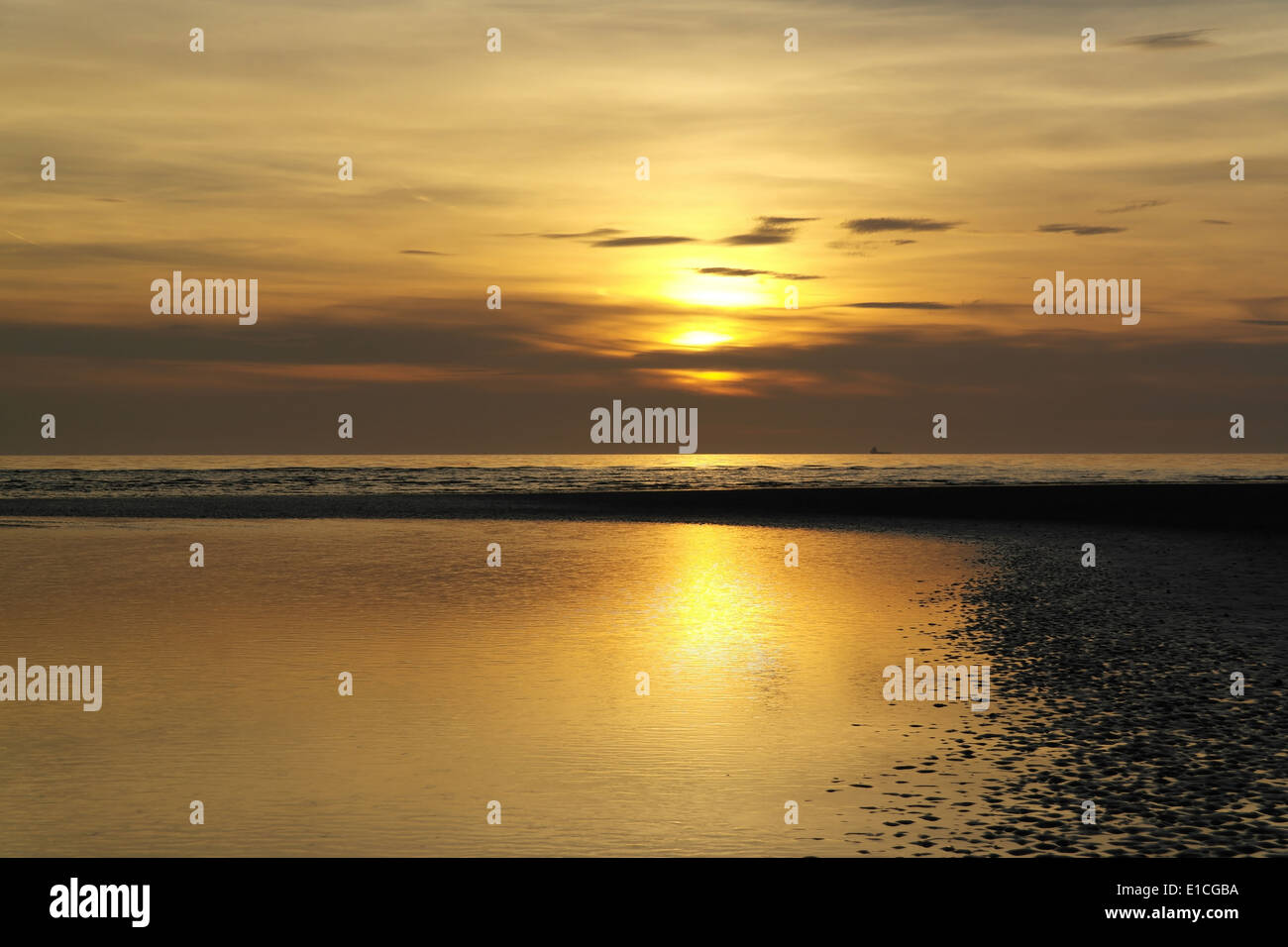 View towards yellow horizon clouds with yellow sunset over beach ...