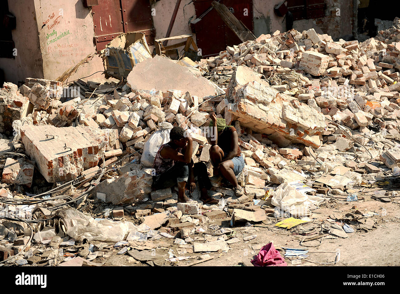 Haitian women sit on rubble from collapsed building in port au prince ...