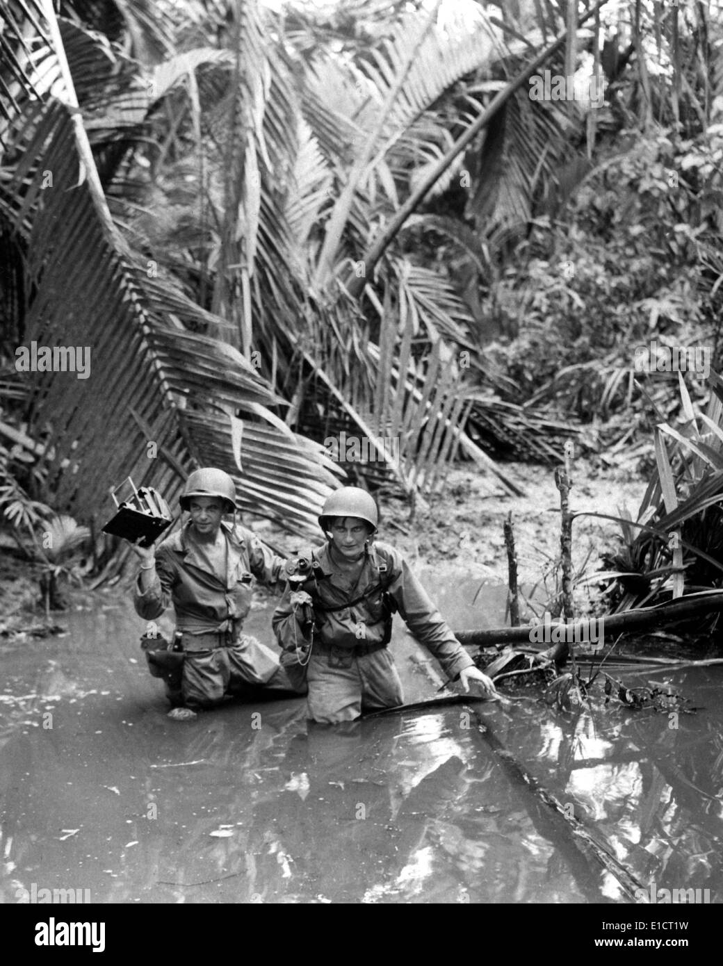 U.S. Army photographer, wading through a stream during an invasion at a ...