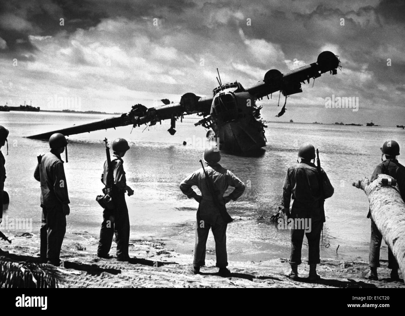 U.S. Army troops look at the ruins of a Japanese seaplane in the lagoon ...