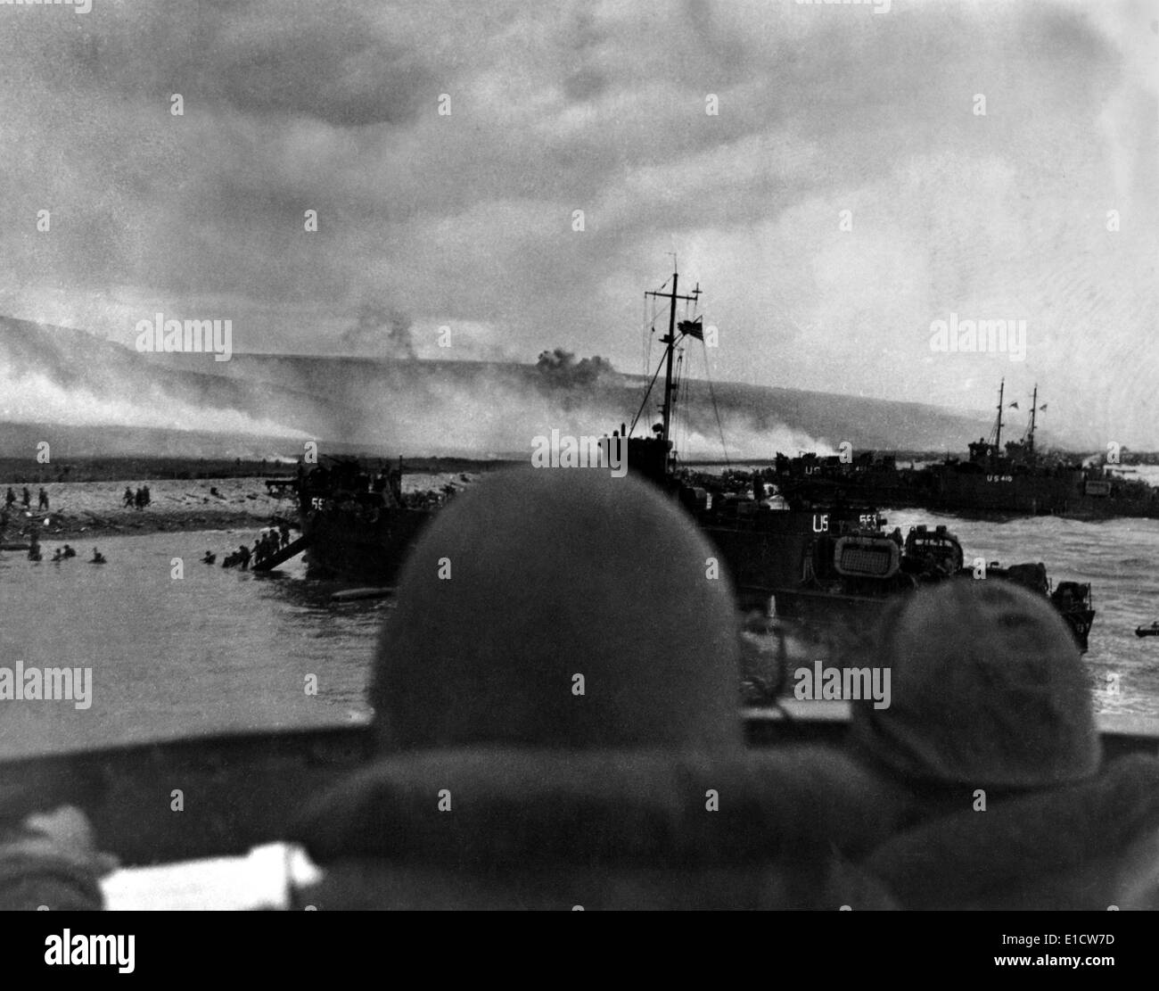 Silhouetted by helmets, view shows two landing craft at Omaha beach on ...