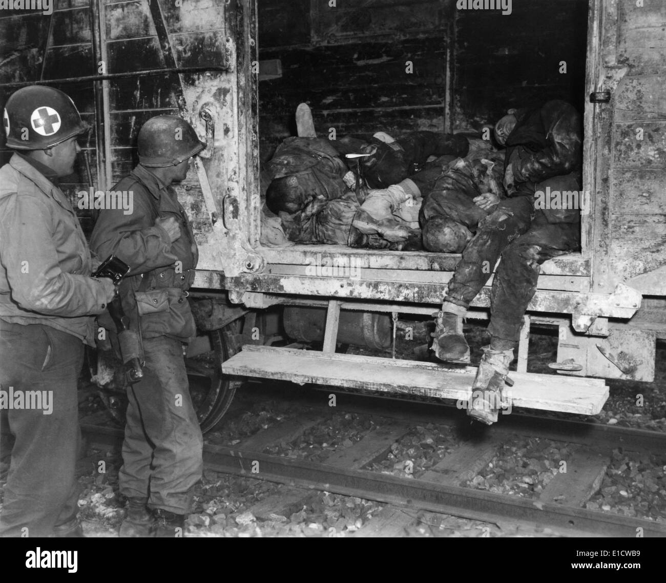Two U.S. soldiers looking at dead prisoners on railroad car at an ...