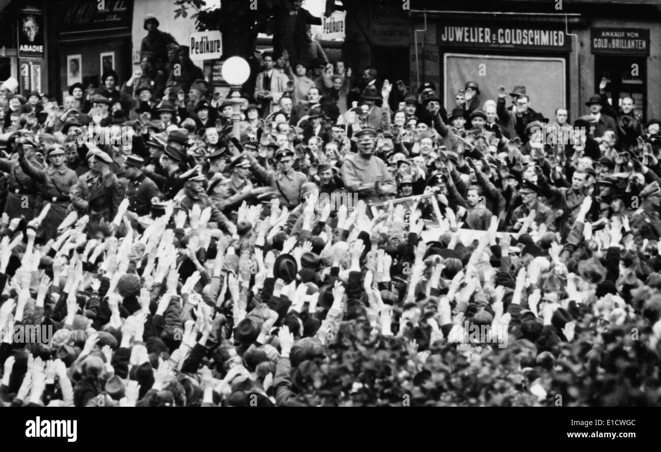 Crowd giving Nazi salute to Adolf Hitler as he stands in an open car ...