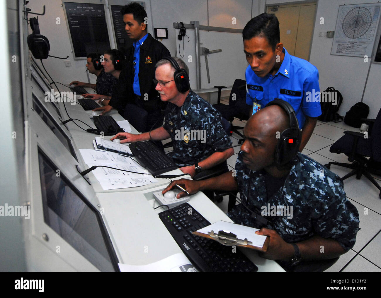 U.S. and Malaysian sailors work on an action speed tactics trainer ...