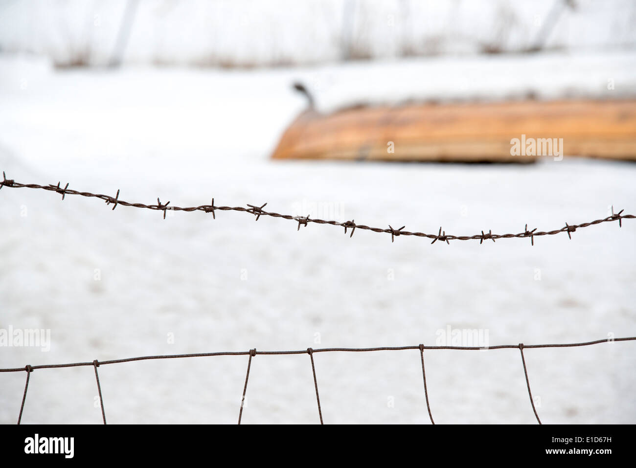 Wooden boat in the snow, behind barbed wire fence Stock Photo - Alamy