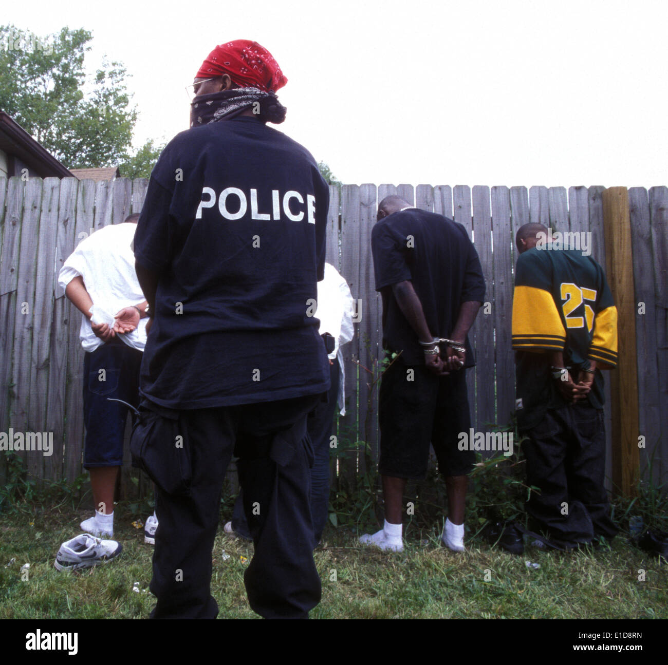 Detroit Narc police officer guards handcuffed suspects during a raid on ...