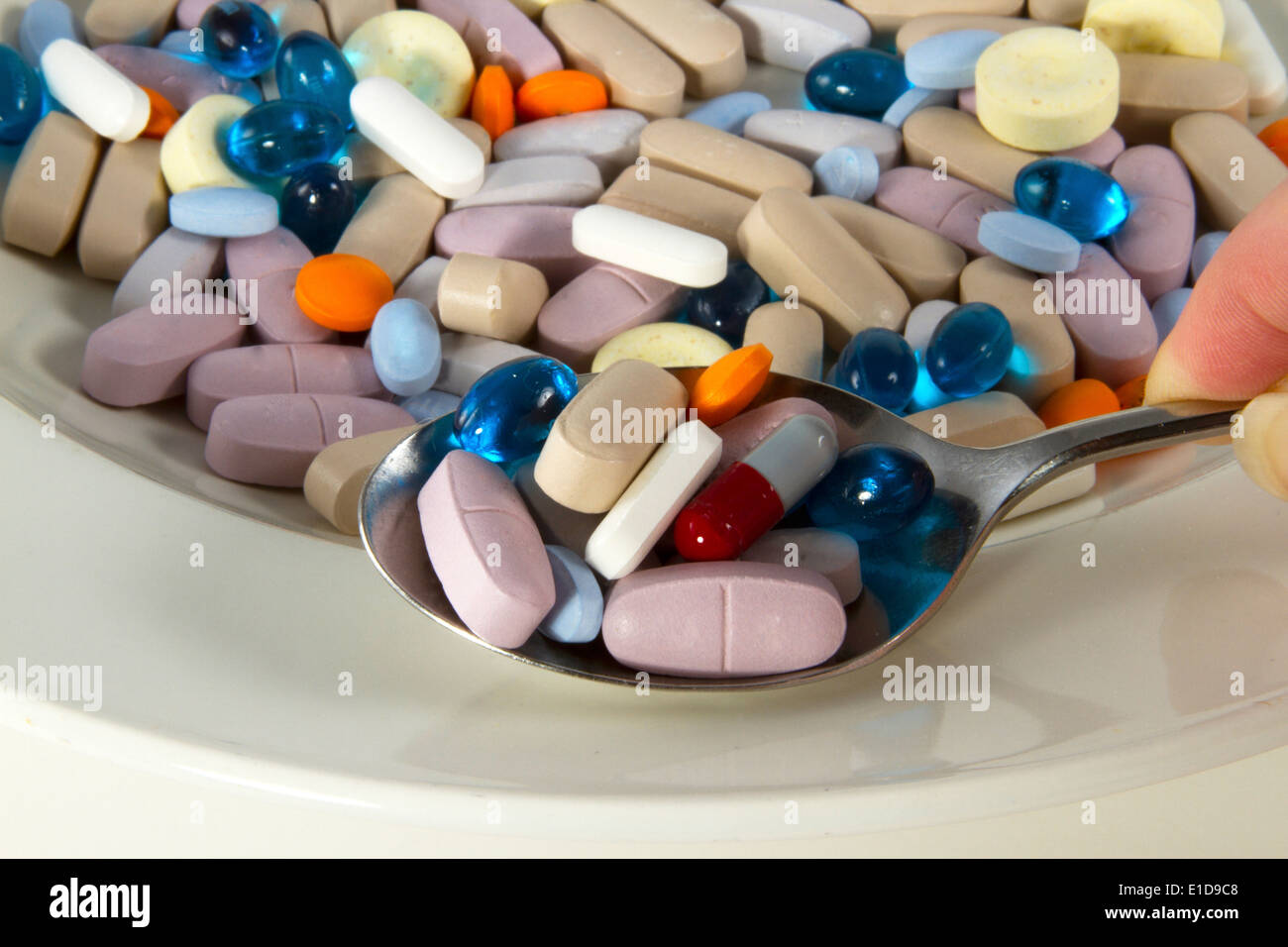 Spoon filled with pills and capsules with a background of a bowl full ...