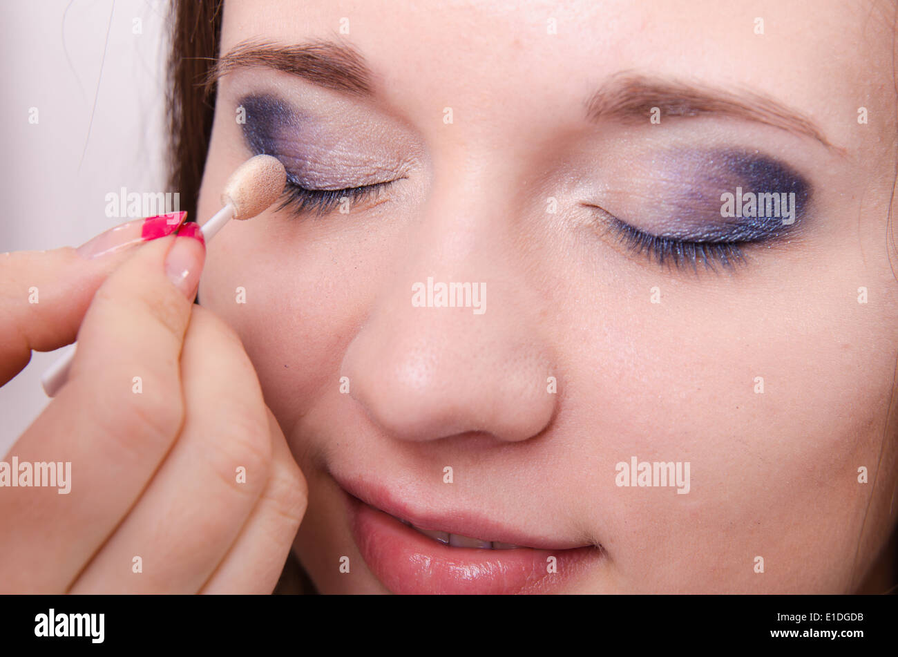 Makeup artist paints the eyelids of a beautiful young girl in the ...