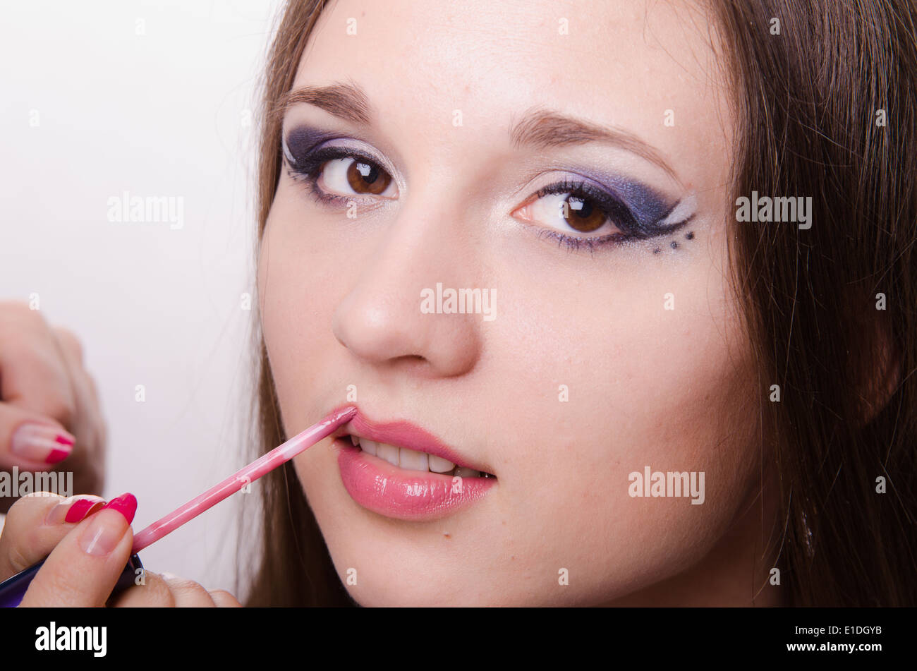 Makeup artist paints her lips a beautiful young girl in the makeup ...