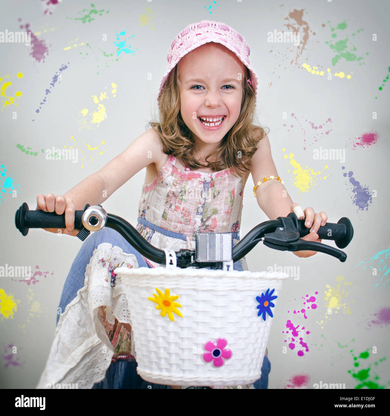 Happy little girl on a bicycle. Painted wall background Stock Photo - Alamy