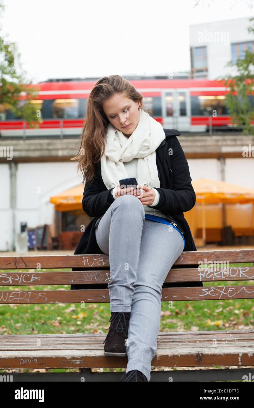 Woman Using Cell Phone On Park Bench Stock Photo - Alamy