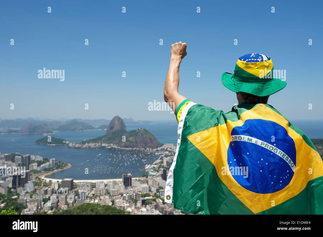 Patriotic Brazilian fan standing wrapped in flag holding up fist pump ...