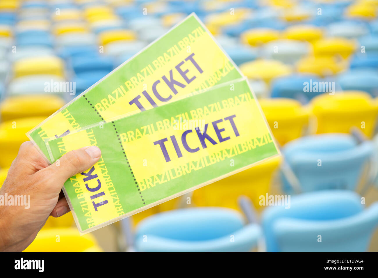 Soccer fan holding two Brazil tickets in front of empty stadium seats ...