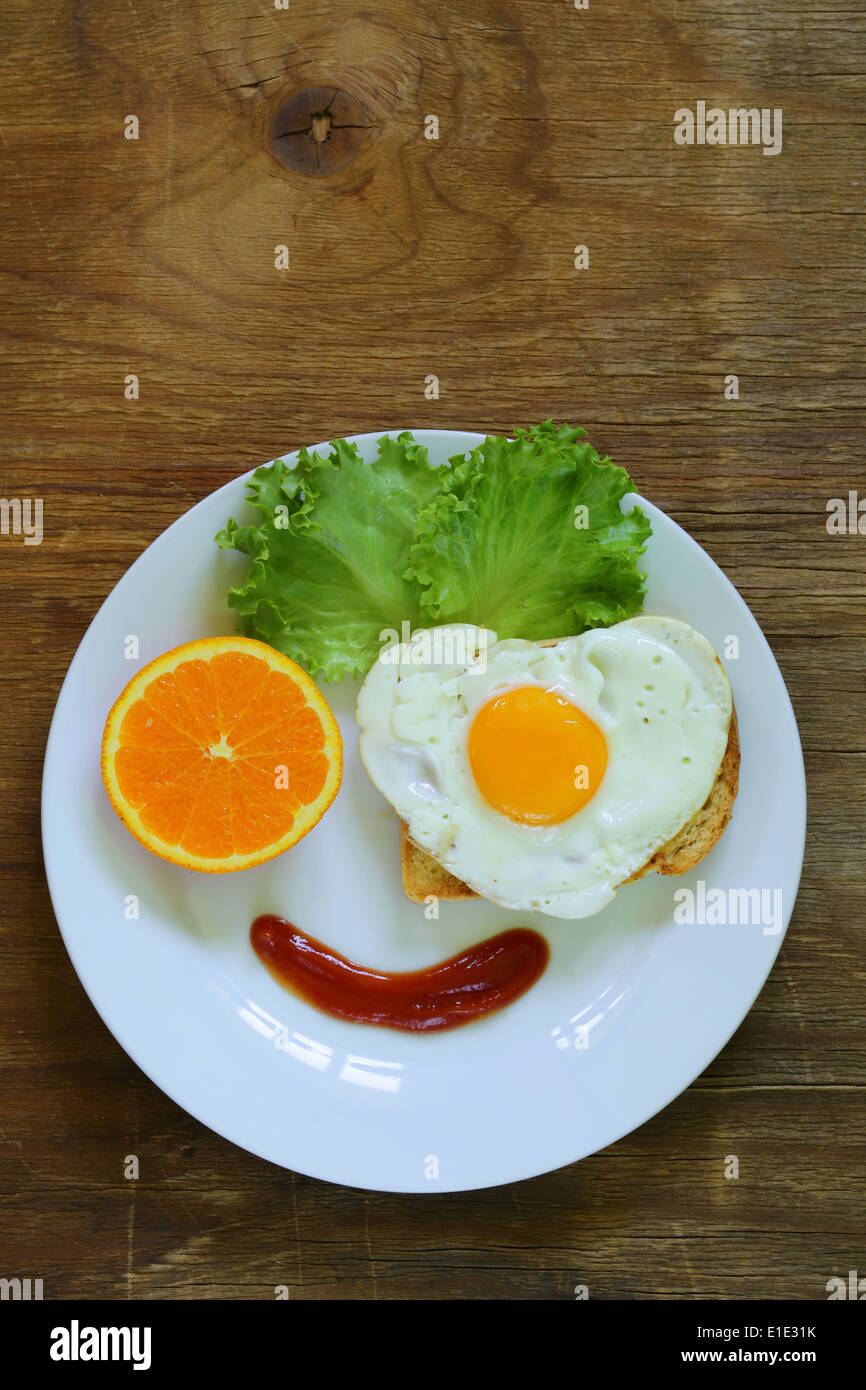 funny face serving breakfast, fried egg, toast and green salad Stock ...