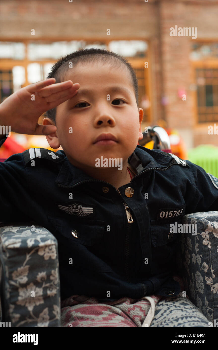 Child with serious expression doing the military salute in an orphanage ...