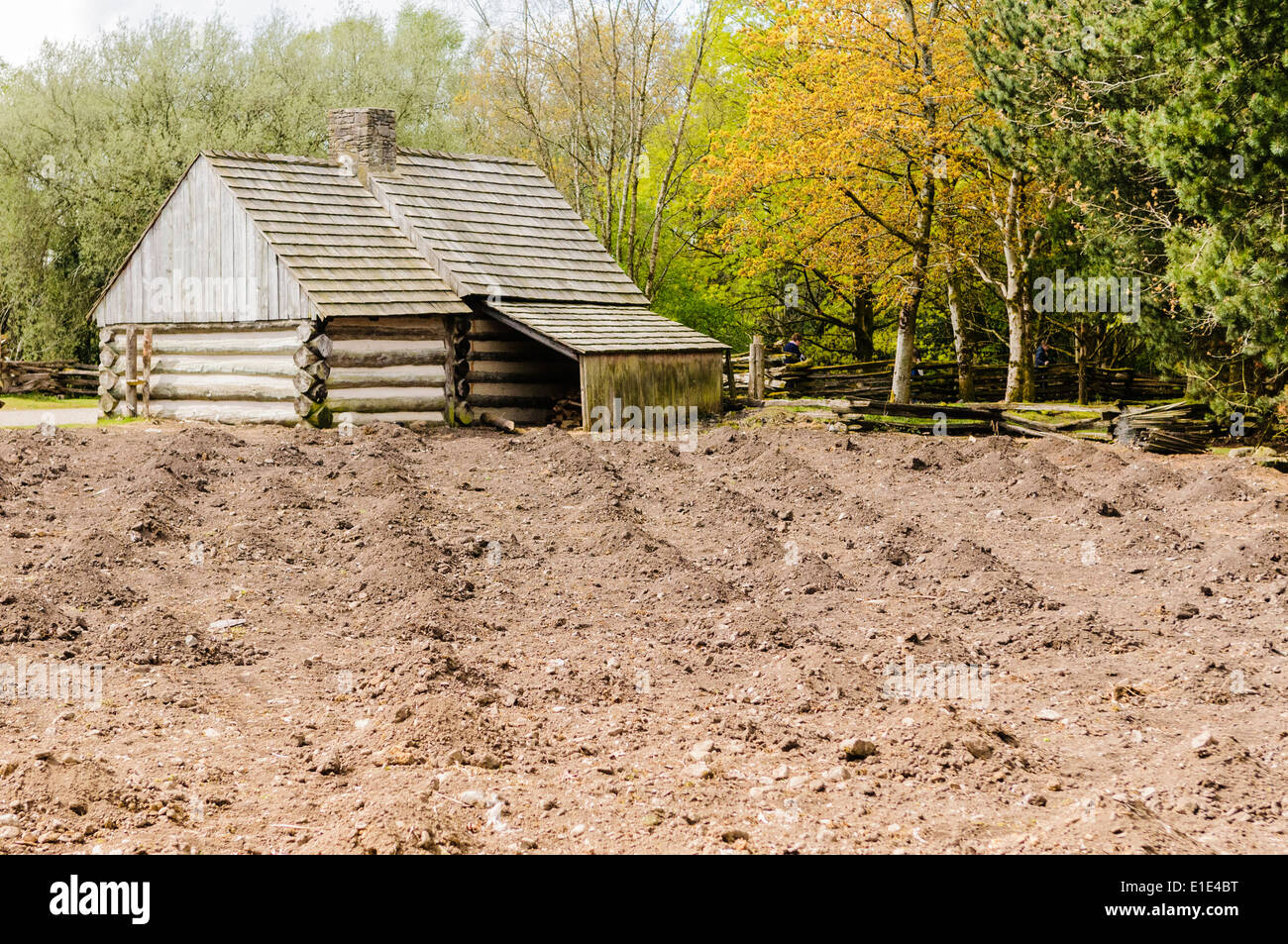 American log cabin with a field dug up ready for planting in the Ulster ...