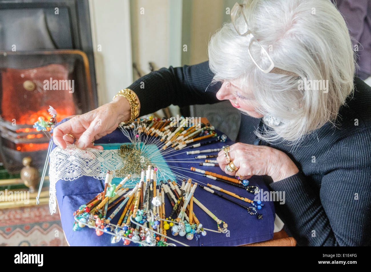 A woman hand-crafts intricate lace using old fashioned bobbins in her ...
