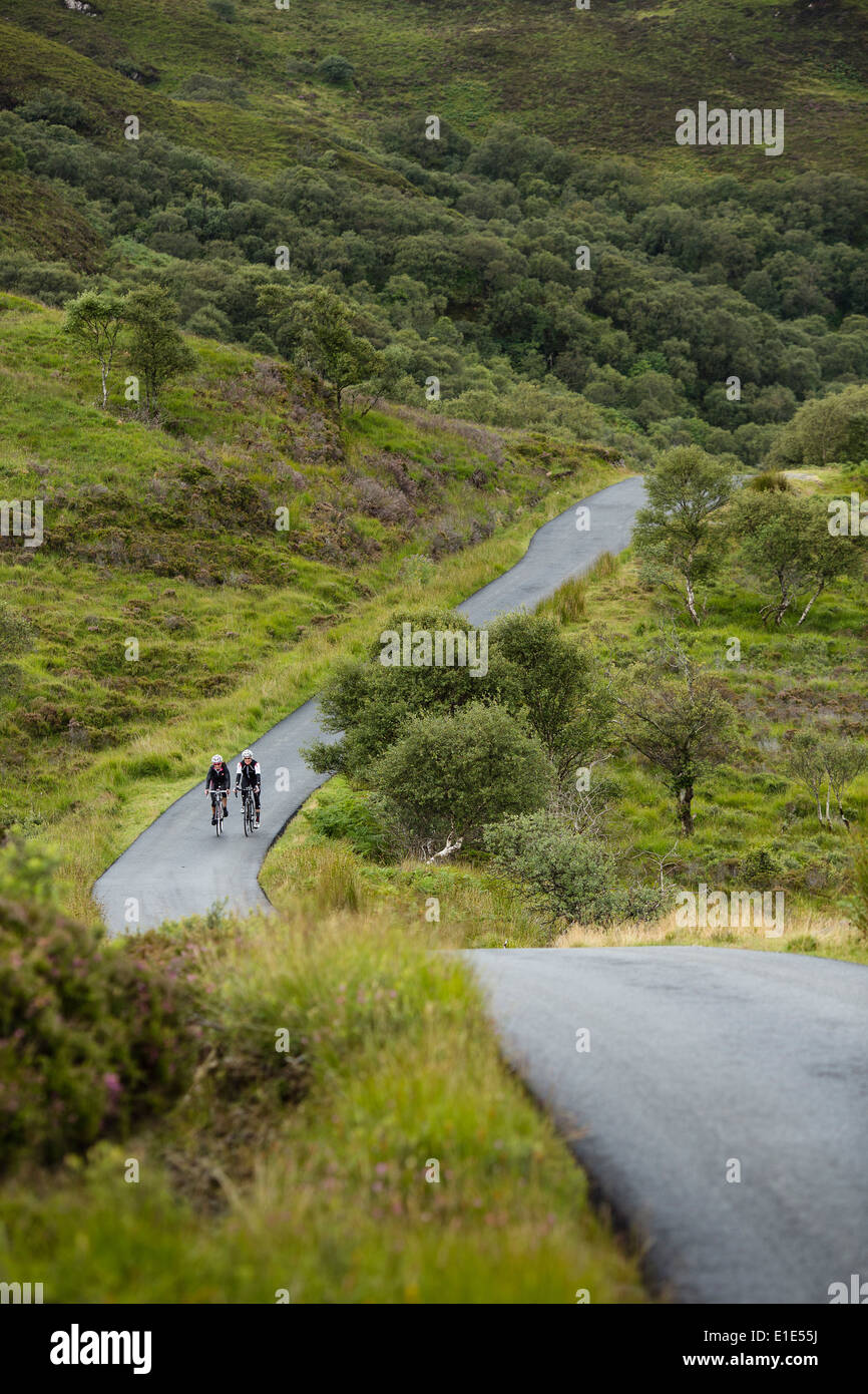 Pair of cyclists ride a path through the countryside on the Isle of ...