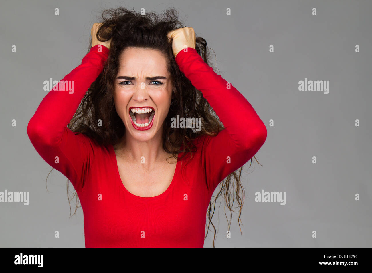 A very frustrated and angry woman is pulling her hair and screaming ...