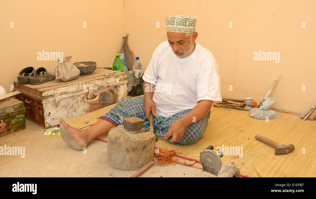 A bearded Omani coppersmith, wearing a traditional kuma (cap), at work ...