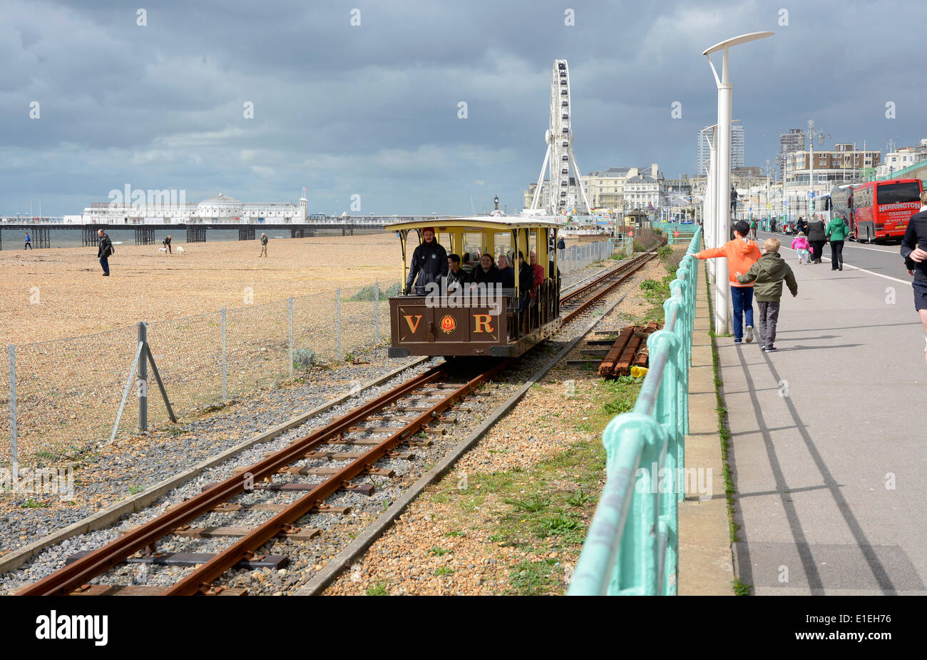 Seafront promenade with Volks electric train on beach. Brighton. East ...