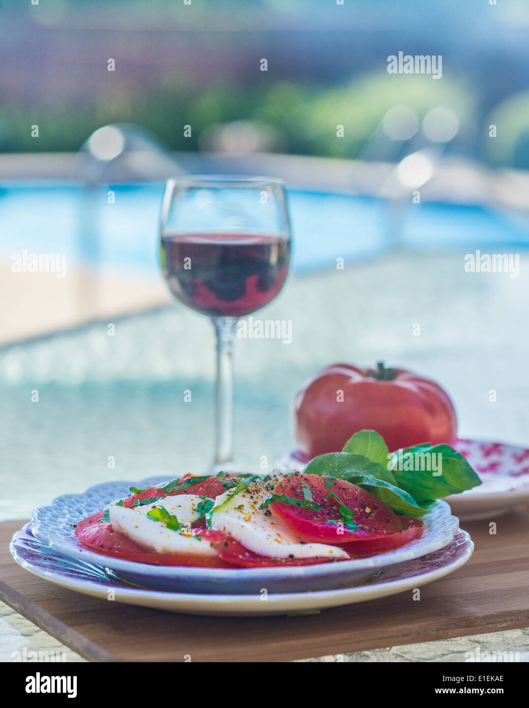Fresh mozzarella cheese sliced with tomatoes at a outdoor pool setting ...