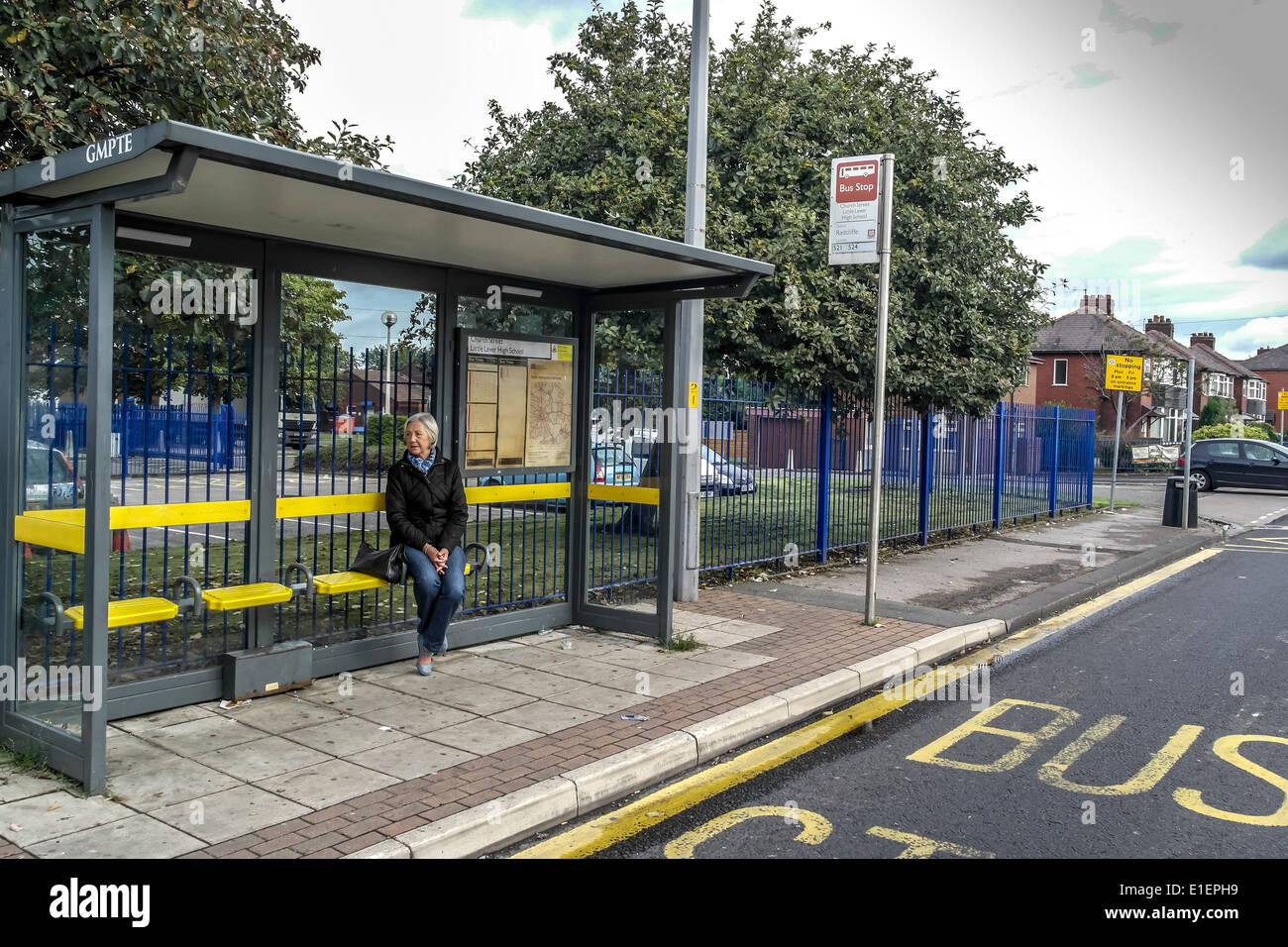 Lady waiting at the bus stop for a bus to come along Stock Photo - Alamy