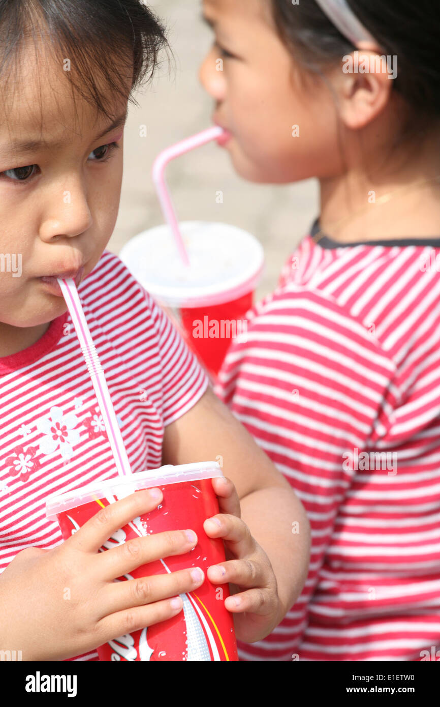 2 sisters having fun with coca cola, both wearing red shirts Stock ...