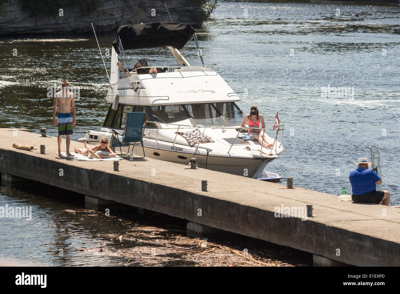 Large boat moored along dock with people relaxing on deck and on the ...