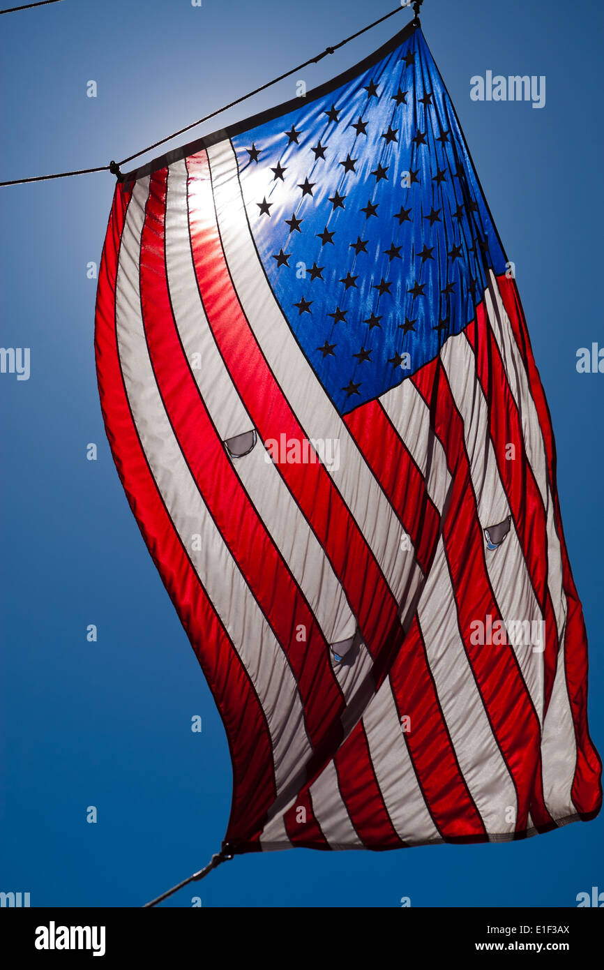US stars and stripes flag flying against the sun in a blue sky ...