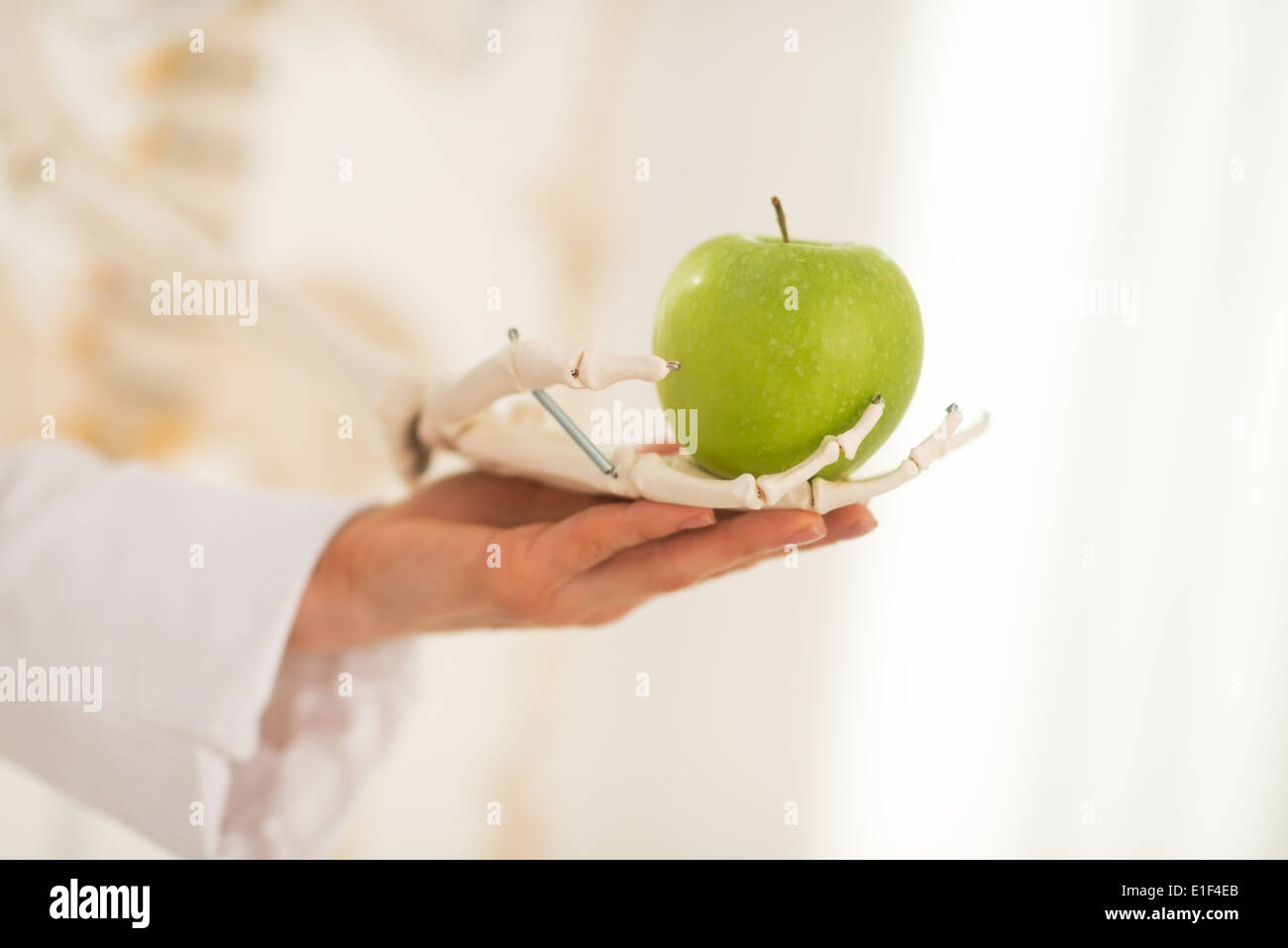 Closeup on medical doctor woman with human skeleton hand holding apple ...