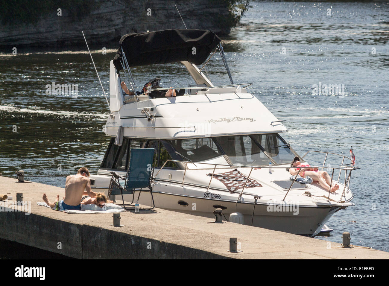 Large boat moored along dock with people relaxing on deck and on the ...
