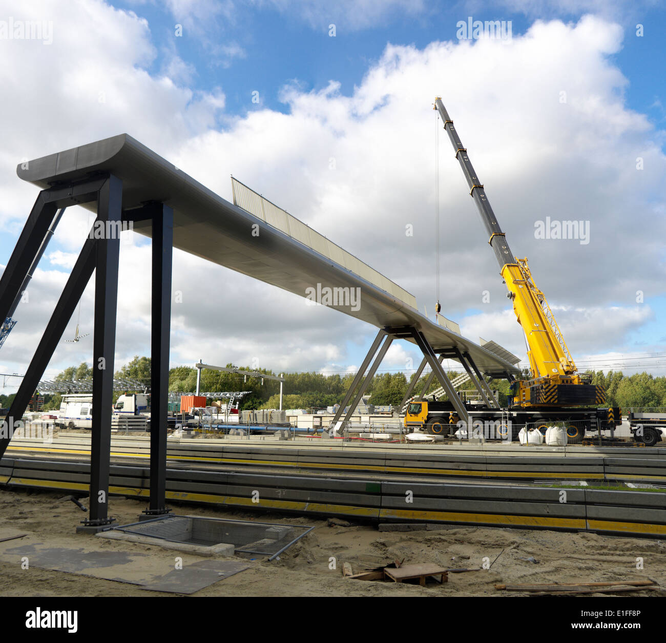 building a foot bridge over a busy road with a large construction crane ...