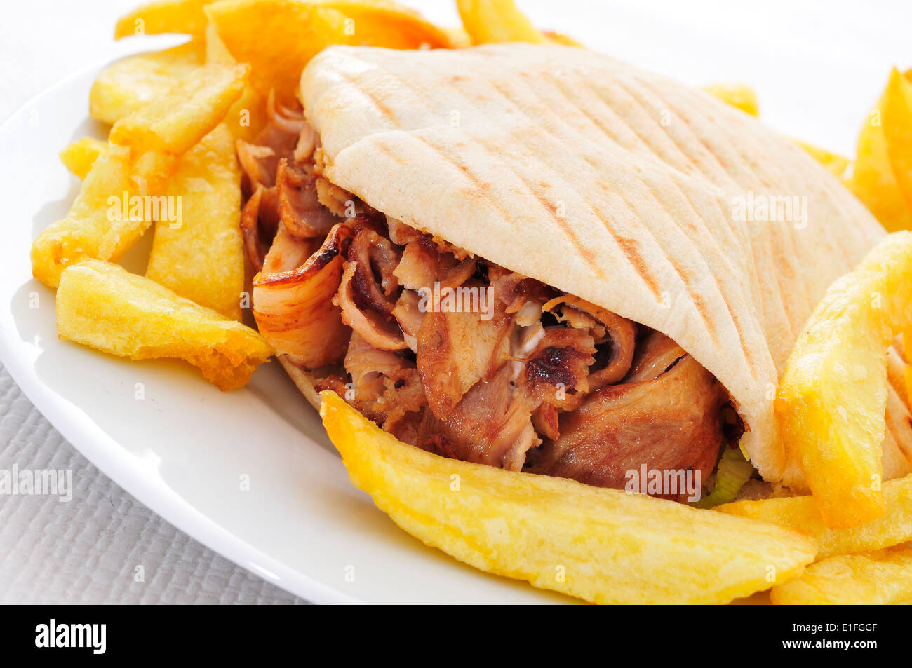 a doner kebab in a plate with french fries on a set table Stock Photo ...